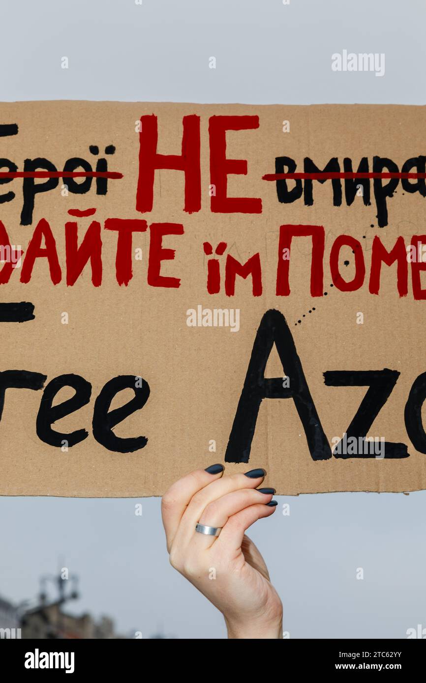 A hand can be seen holding a placard against the sky with the words ...