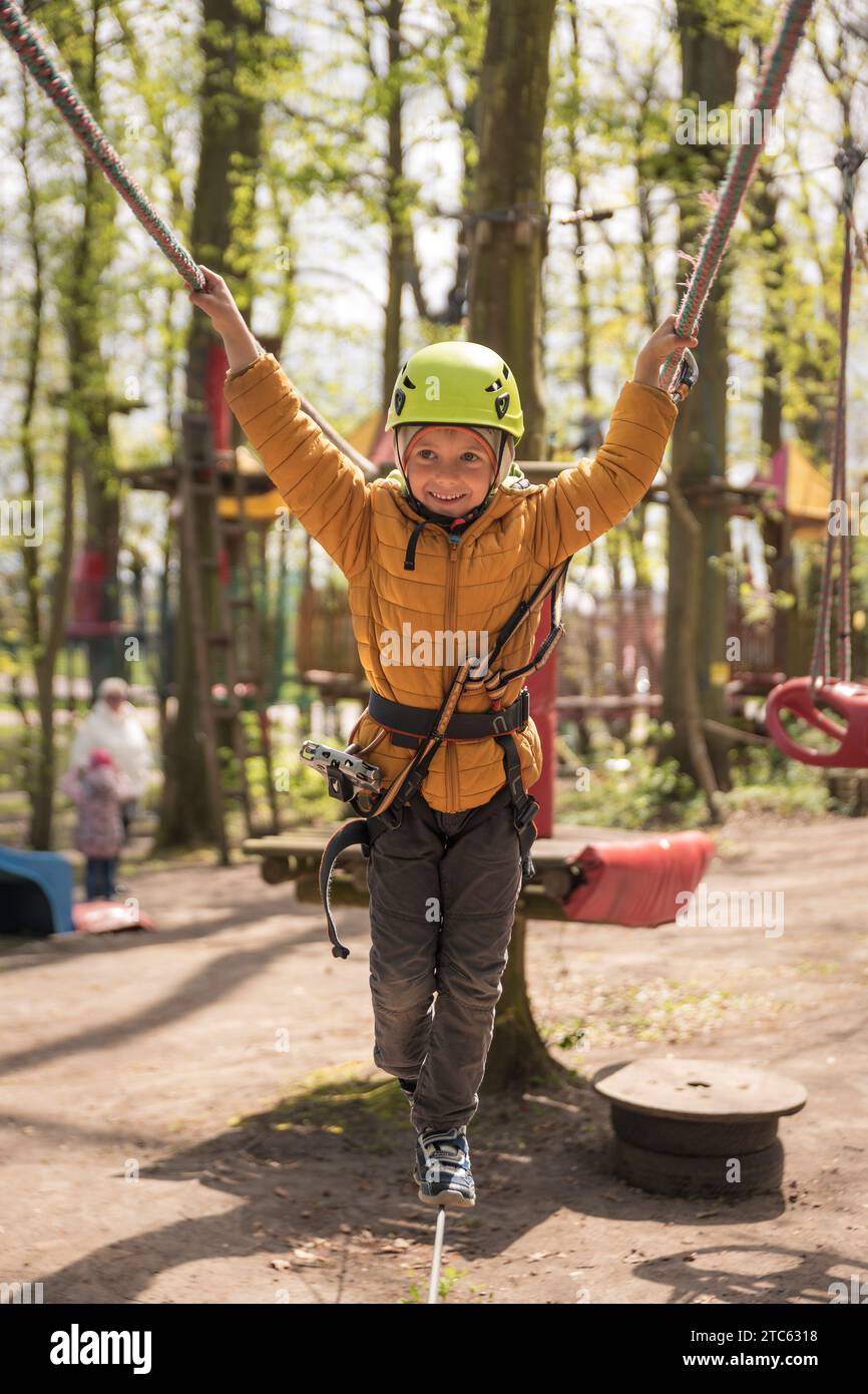 Portrait of cute little boy walk on a rope in an adventure rope park ...