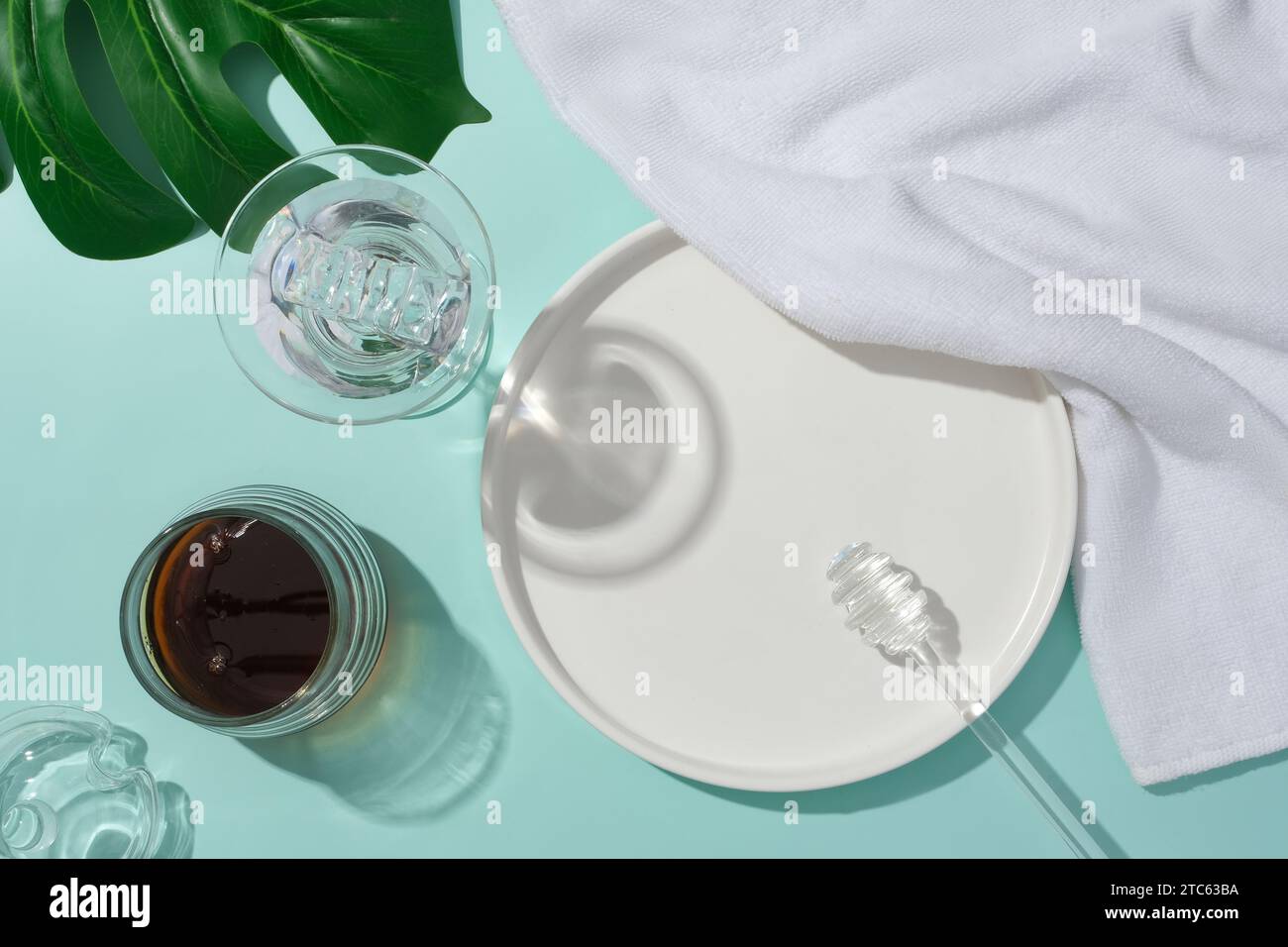 White ceramic plate, honey, glass of water, and props showcased from a ...