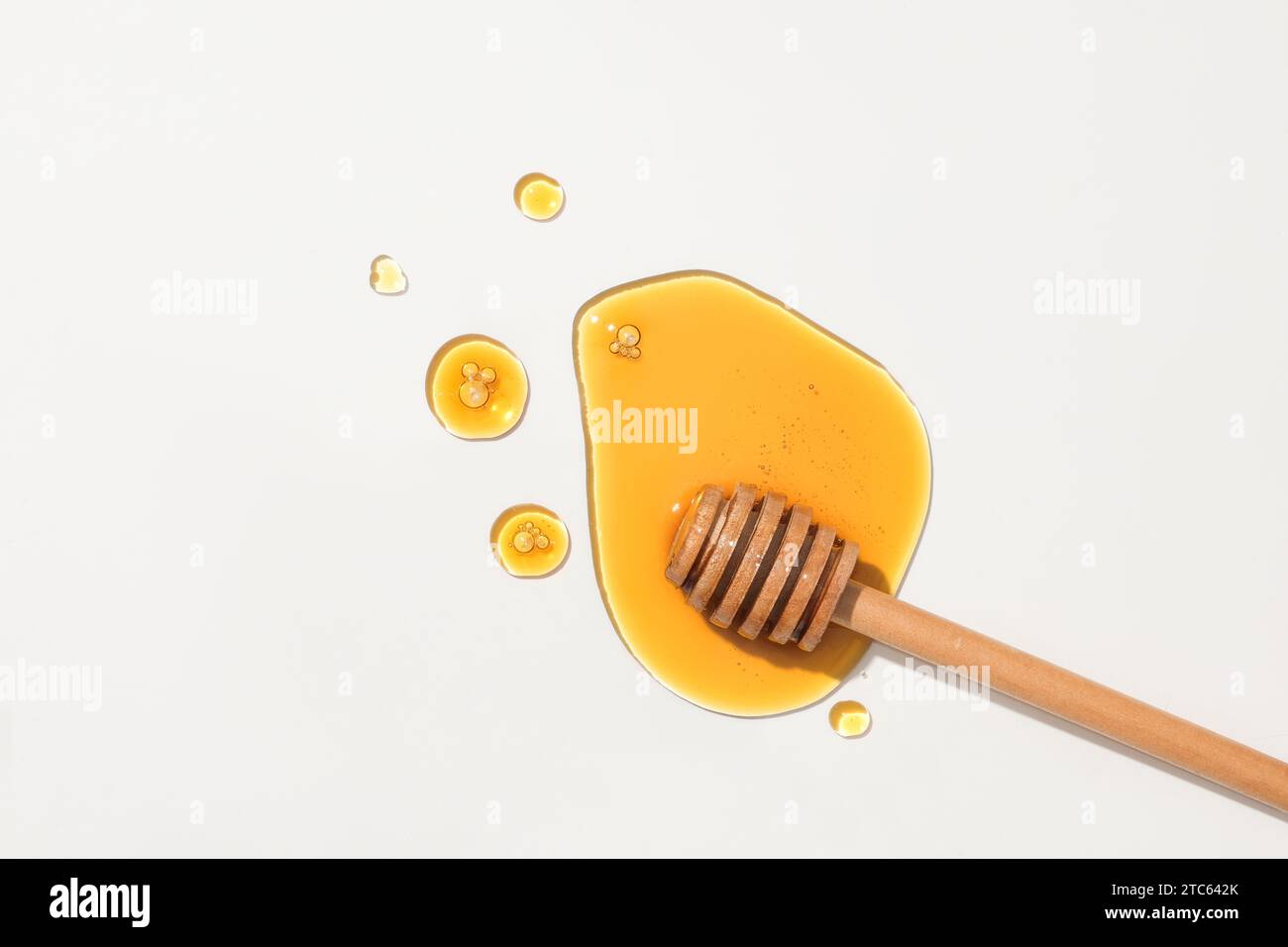 Honey and a wooden honey drizzle displayed on a white background ...
