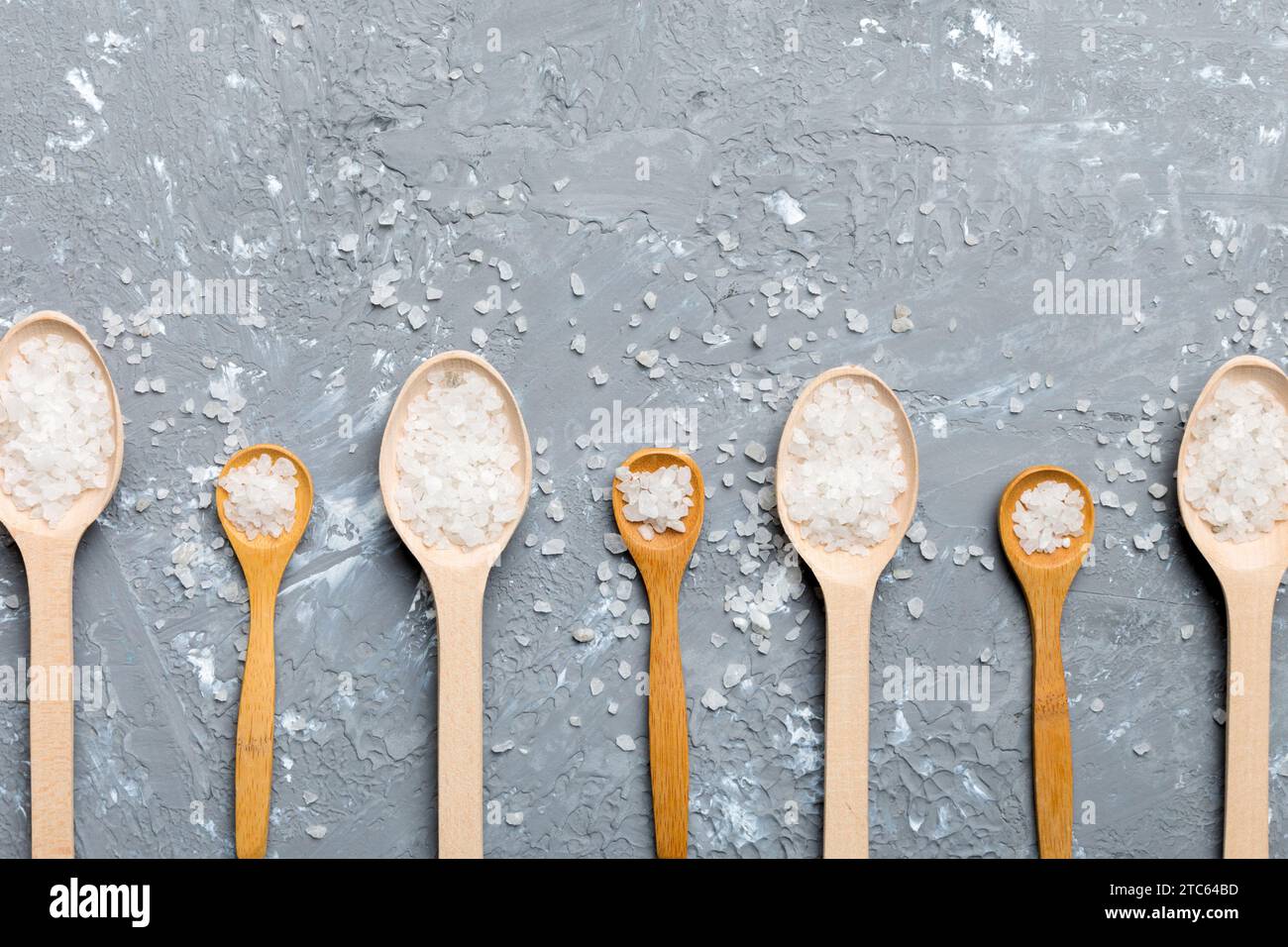 salt on many wooden spoon on wood background. Spoons with different ...