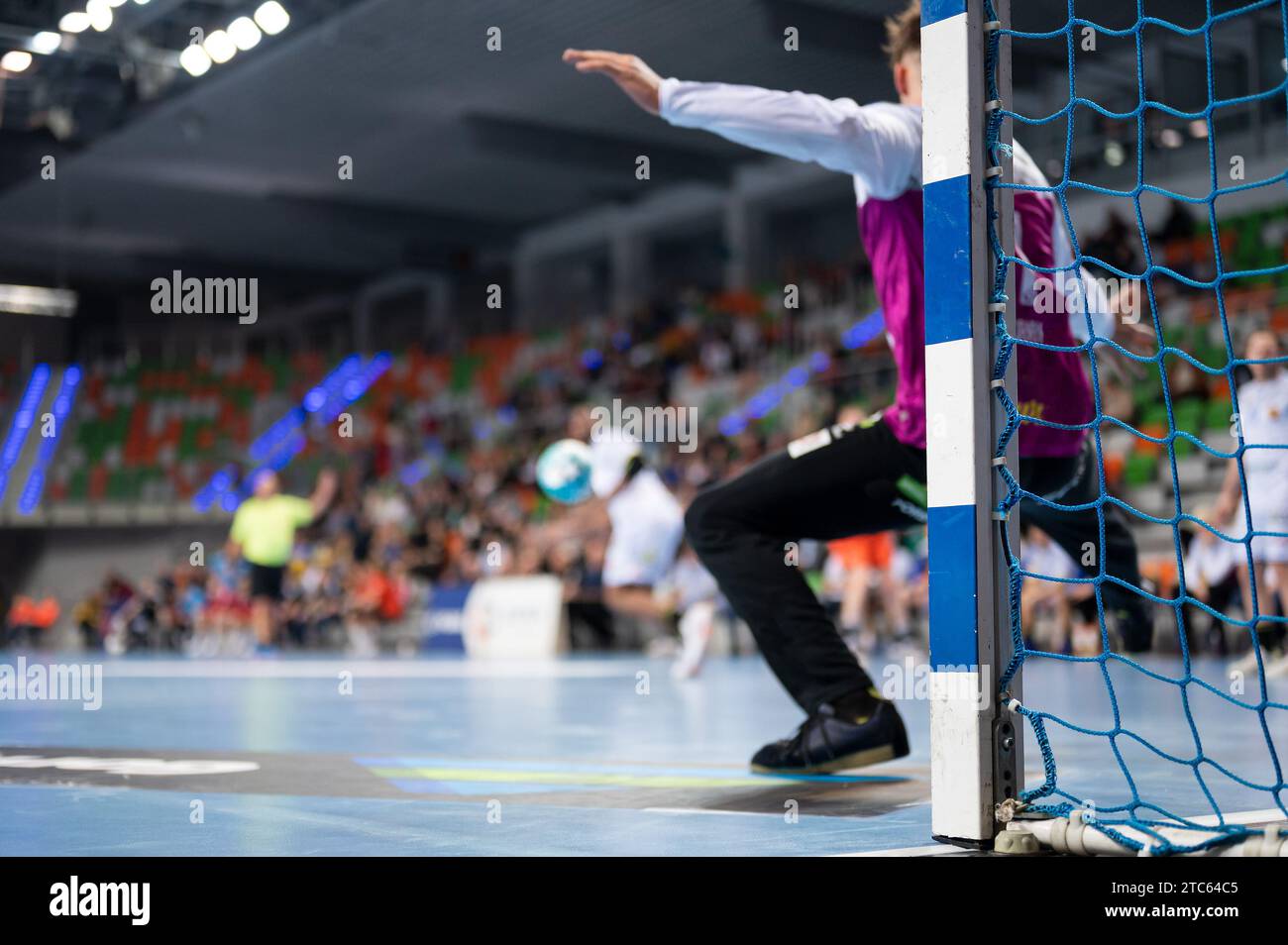 Detail of handball goal post with net and players in the background ...