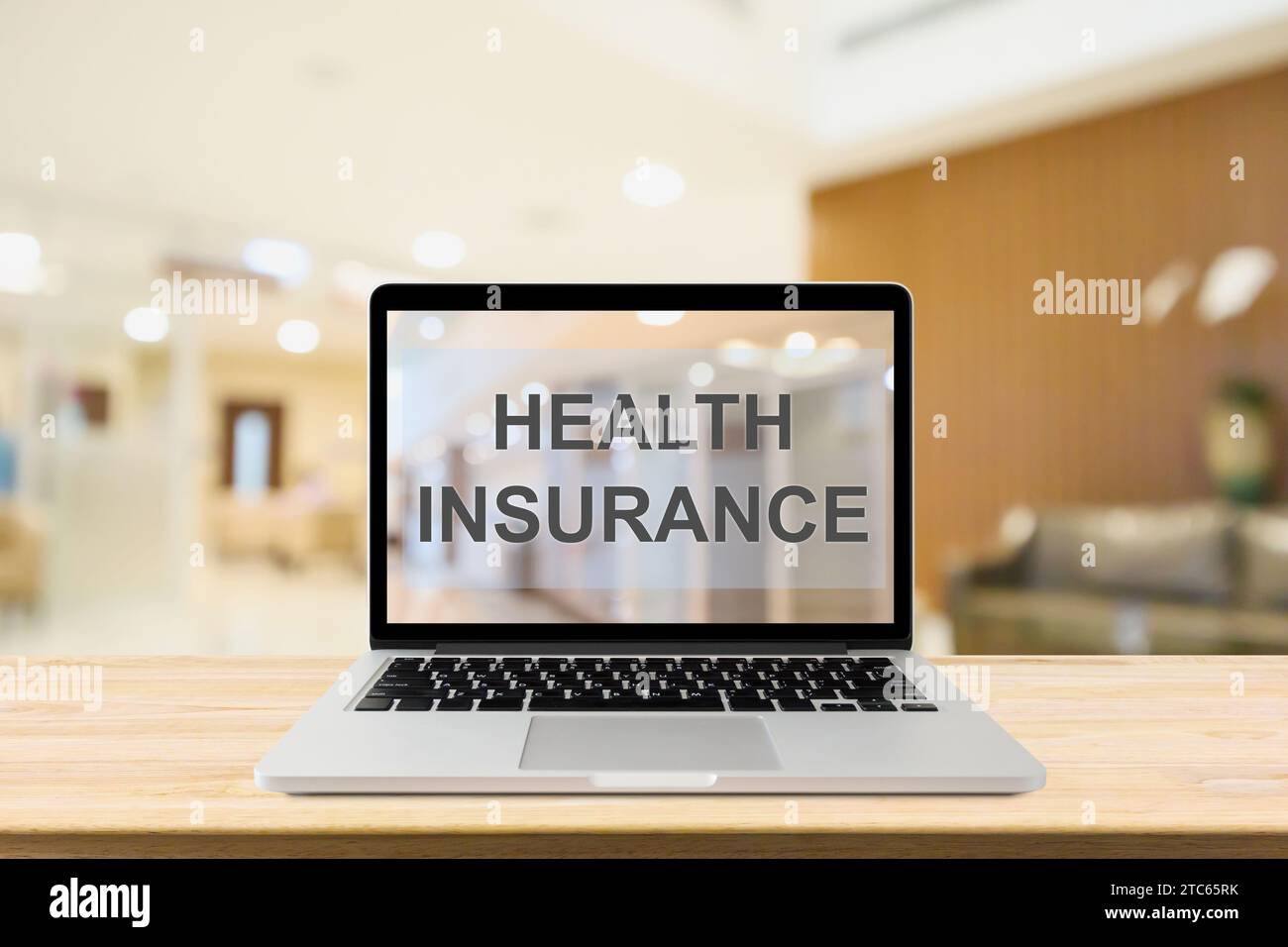 Laptop computer on wood table with Health Insurance text on screen with ...