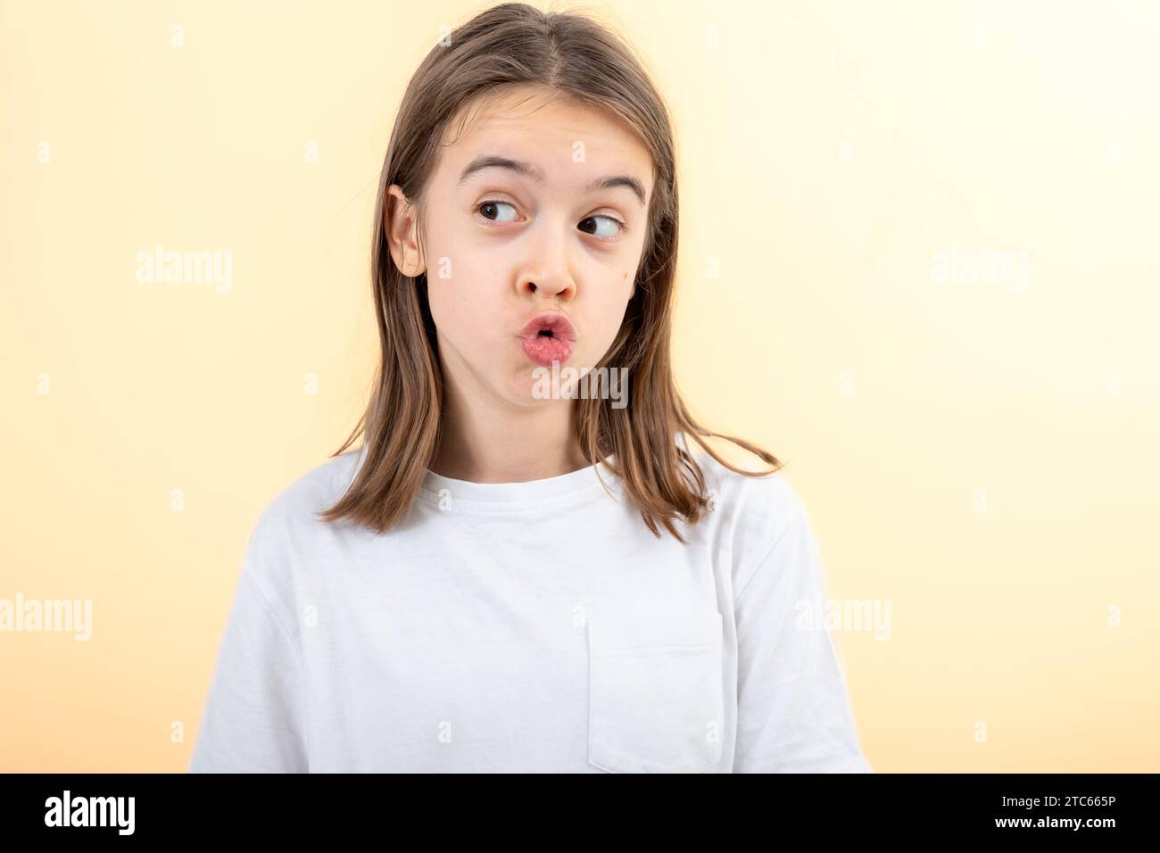 A Teenage Girl Grimaces With Her Lips Pursed Into A Tube On A Yellow
