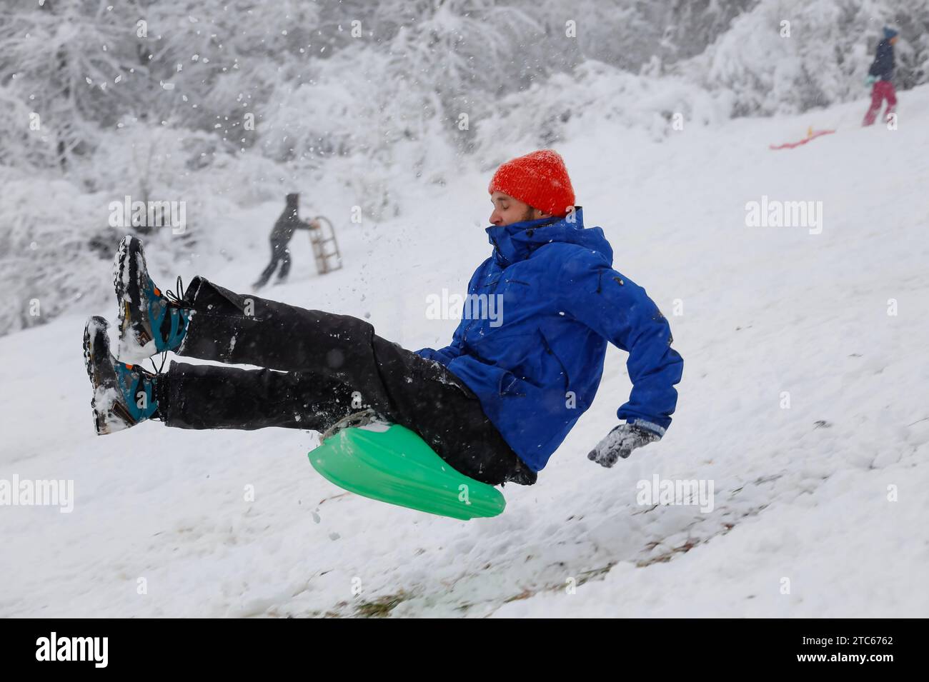 Man sleighing down a snowy hill flying through the air in Munich ...