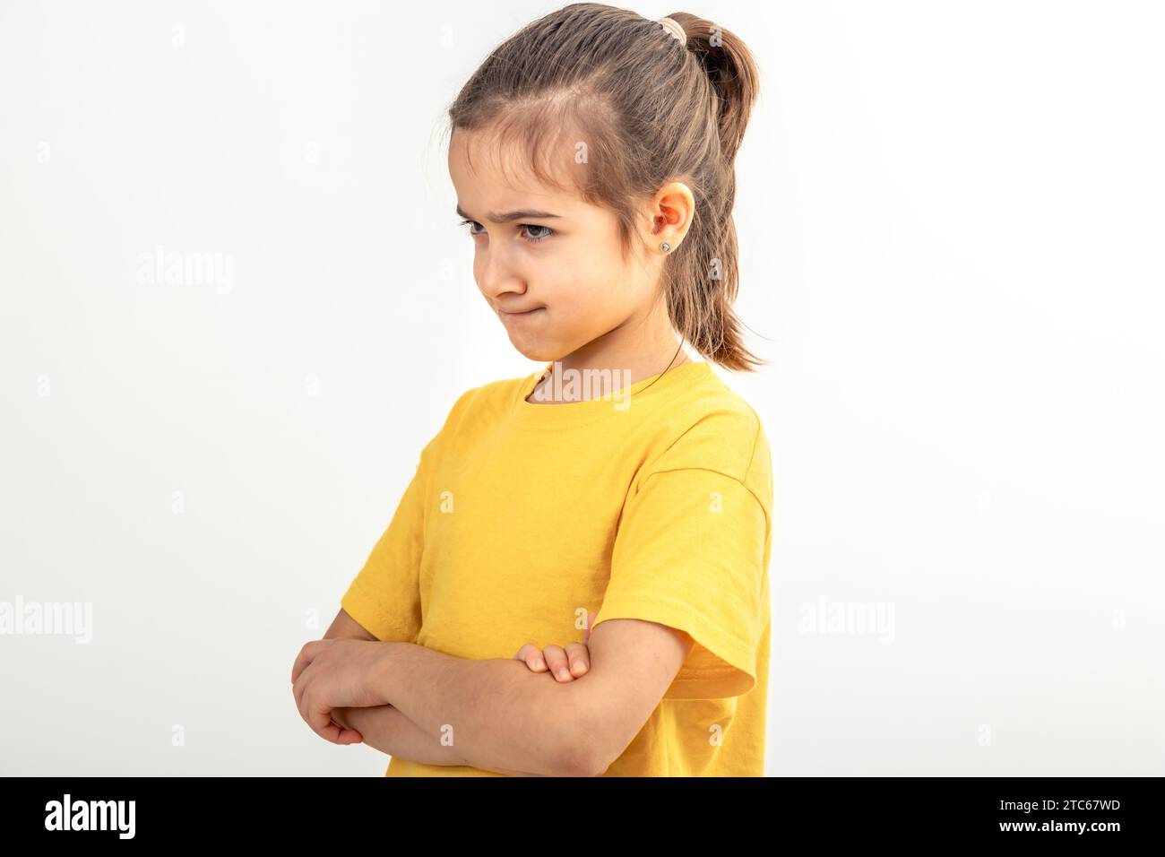 Angry little girl with folded hands on a white background isolated ...