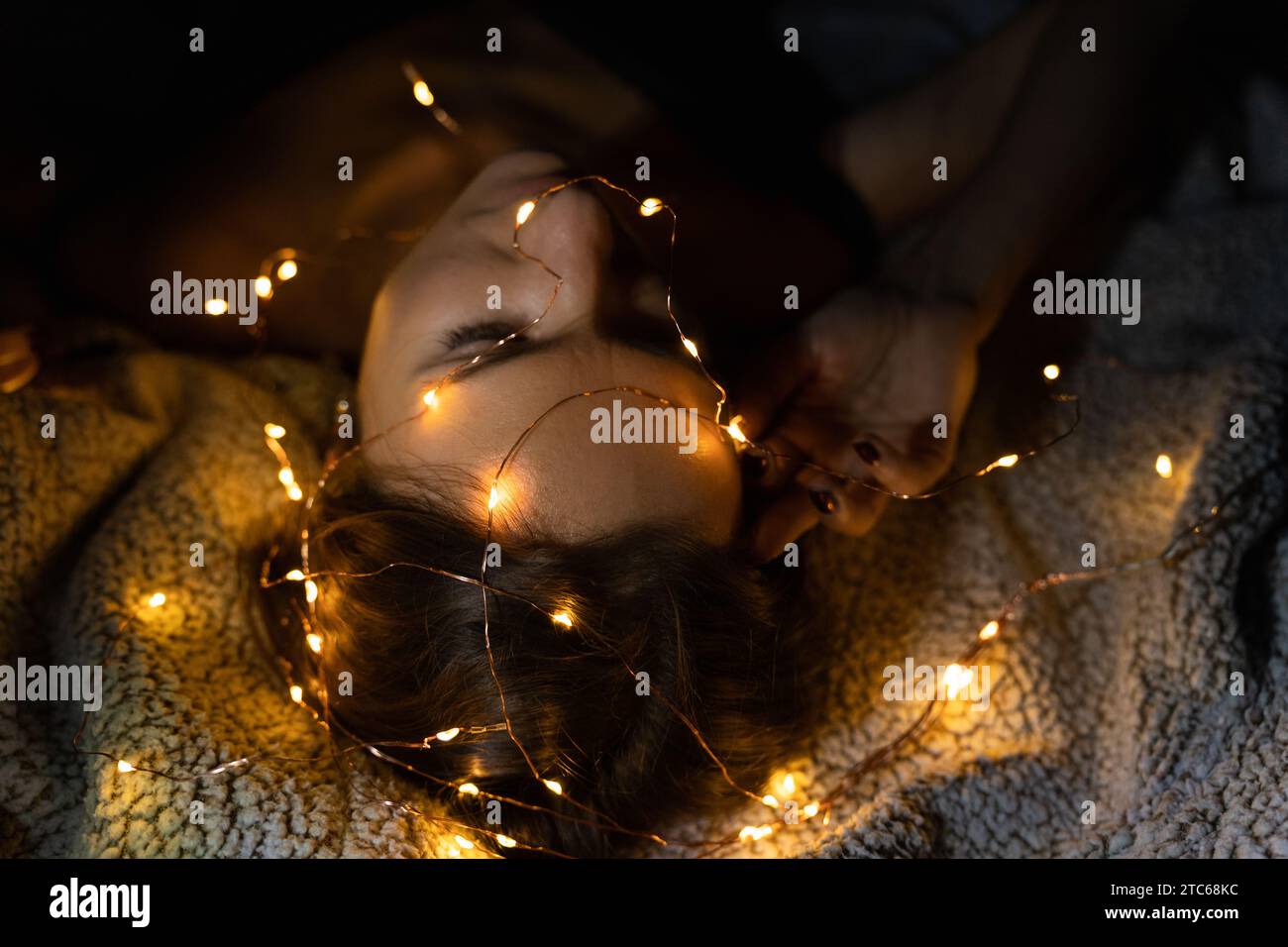 Reclining woman with her eyes closed and many glowing fairy lights ...