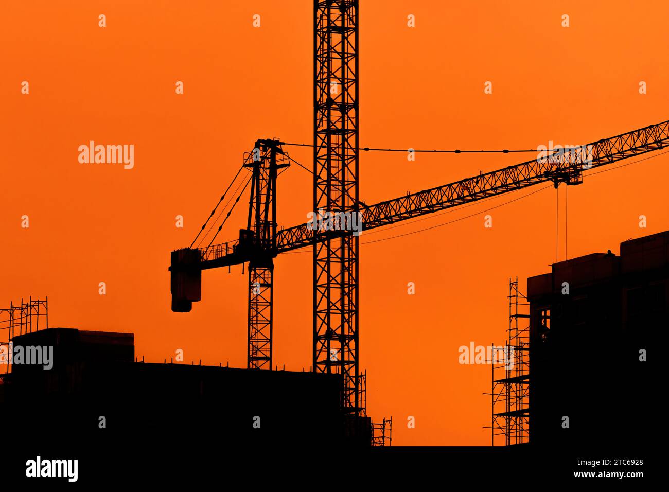 Silhouette of construction crane, scaffolding and buildings in sunset ...