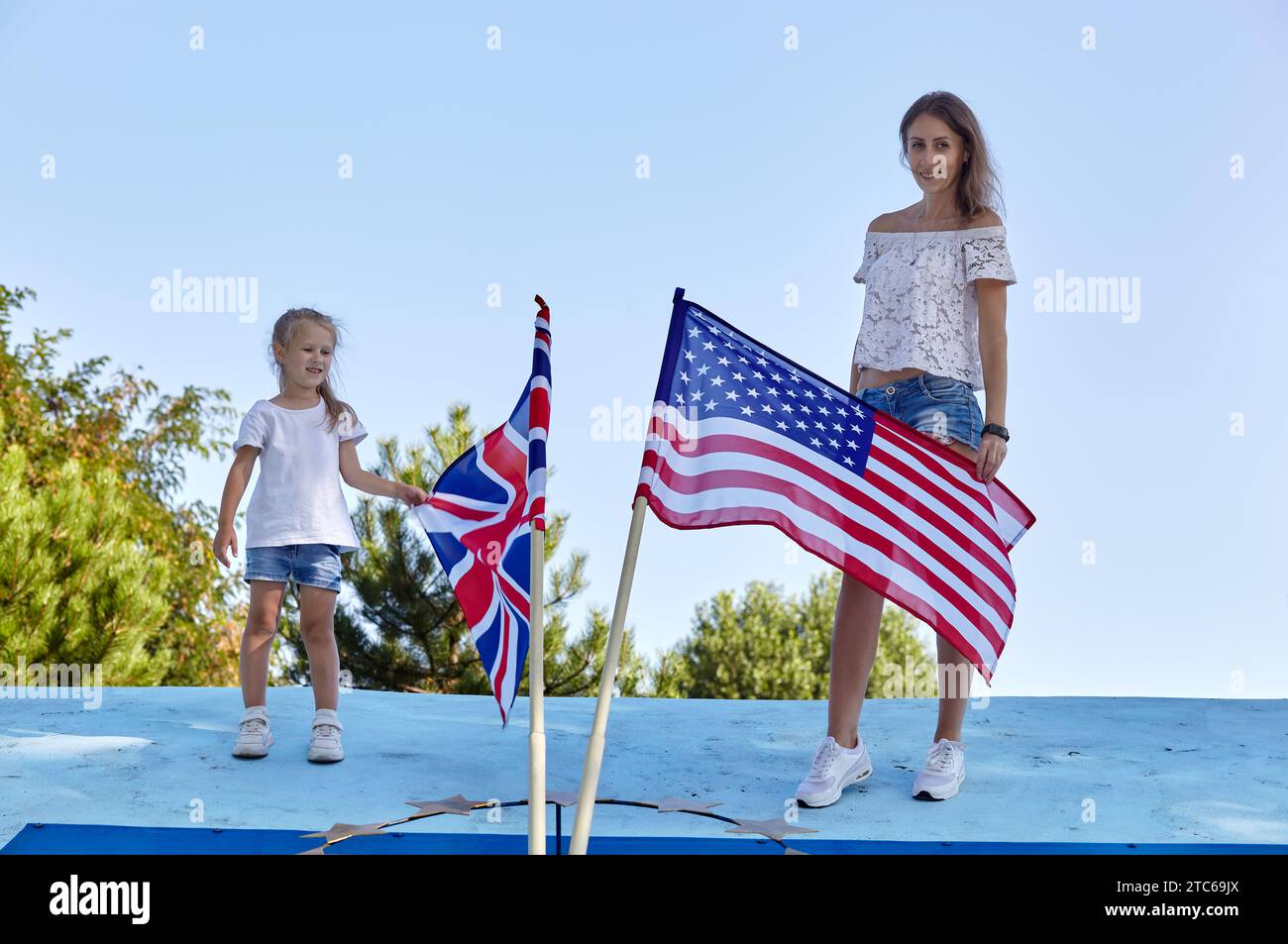 Mother with american flag and daughter with big Britain flag in their ...