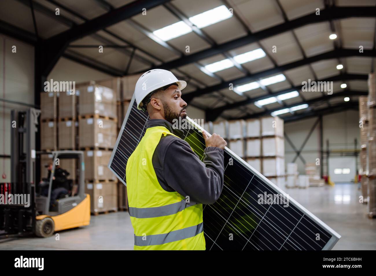 Handsome worker carrying solar panel in warehouse, factory. Solar panel ...