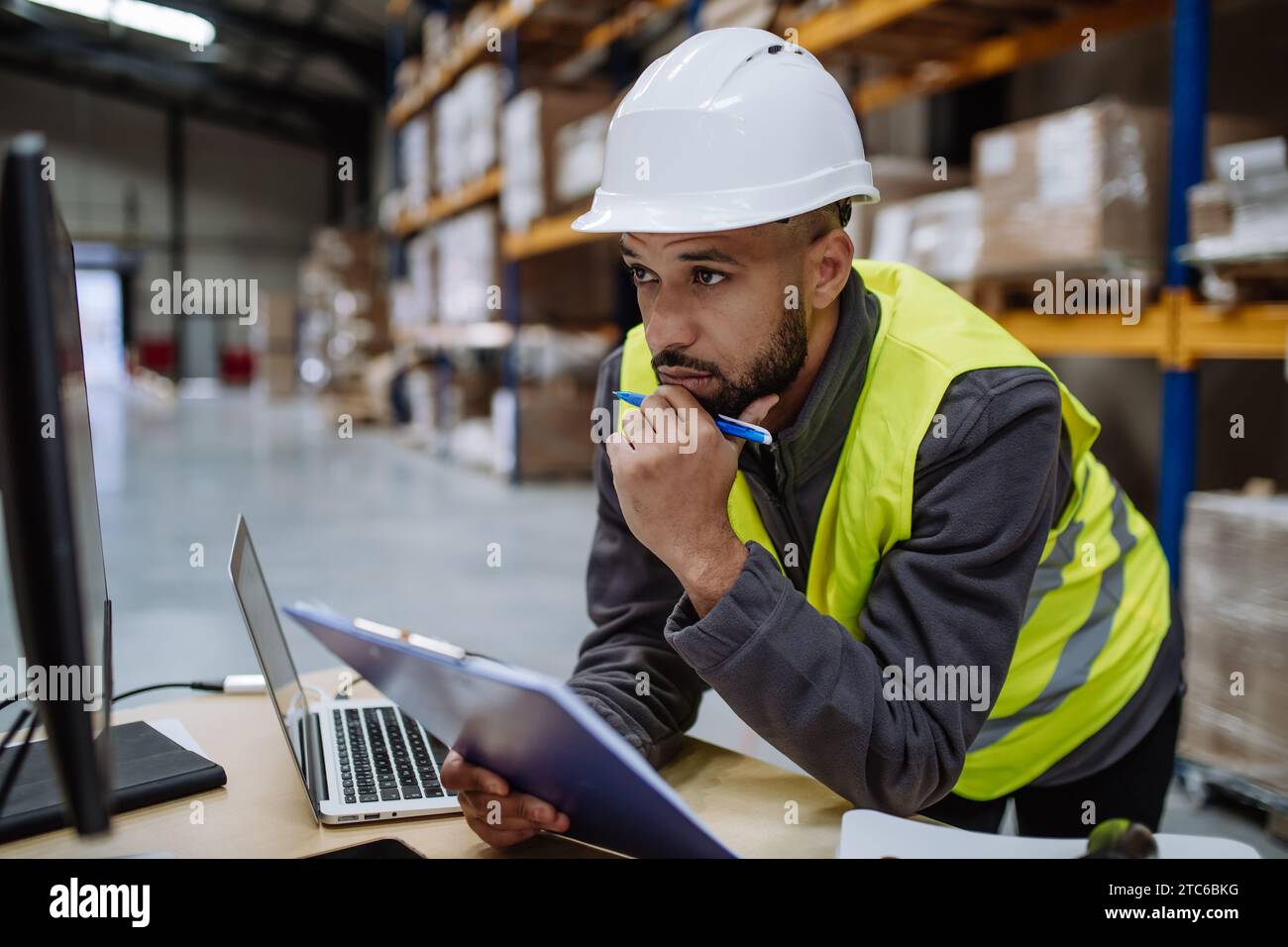 Warehouseman checking delivery, stock in warehouse on computer, pc ...