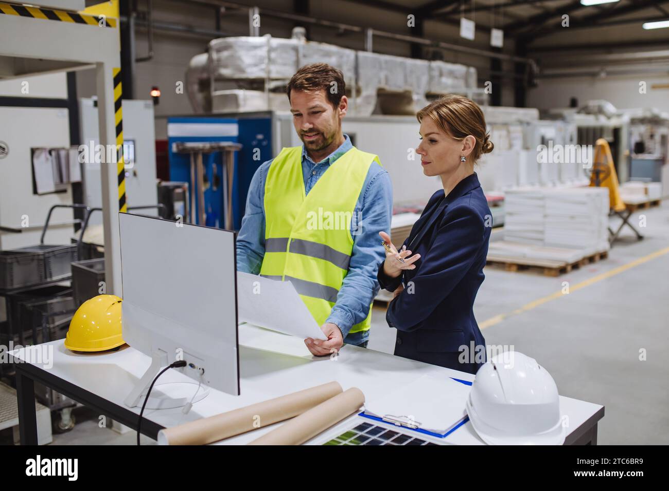 Female engineer reading technical documentation with project manager in ...