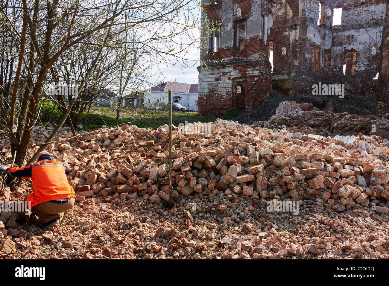 Workers collect bricks from the collapsed wall of an old abandoned ...
