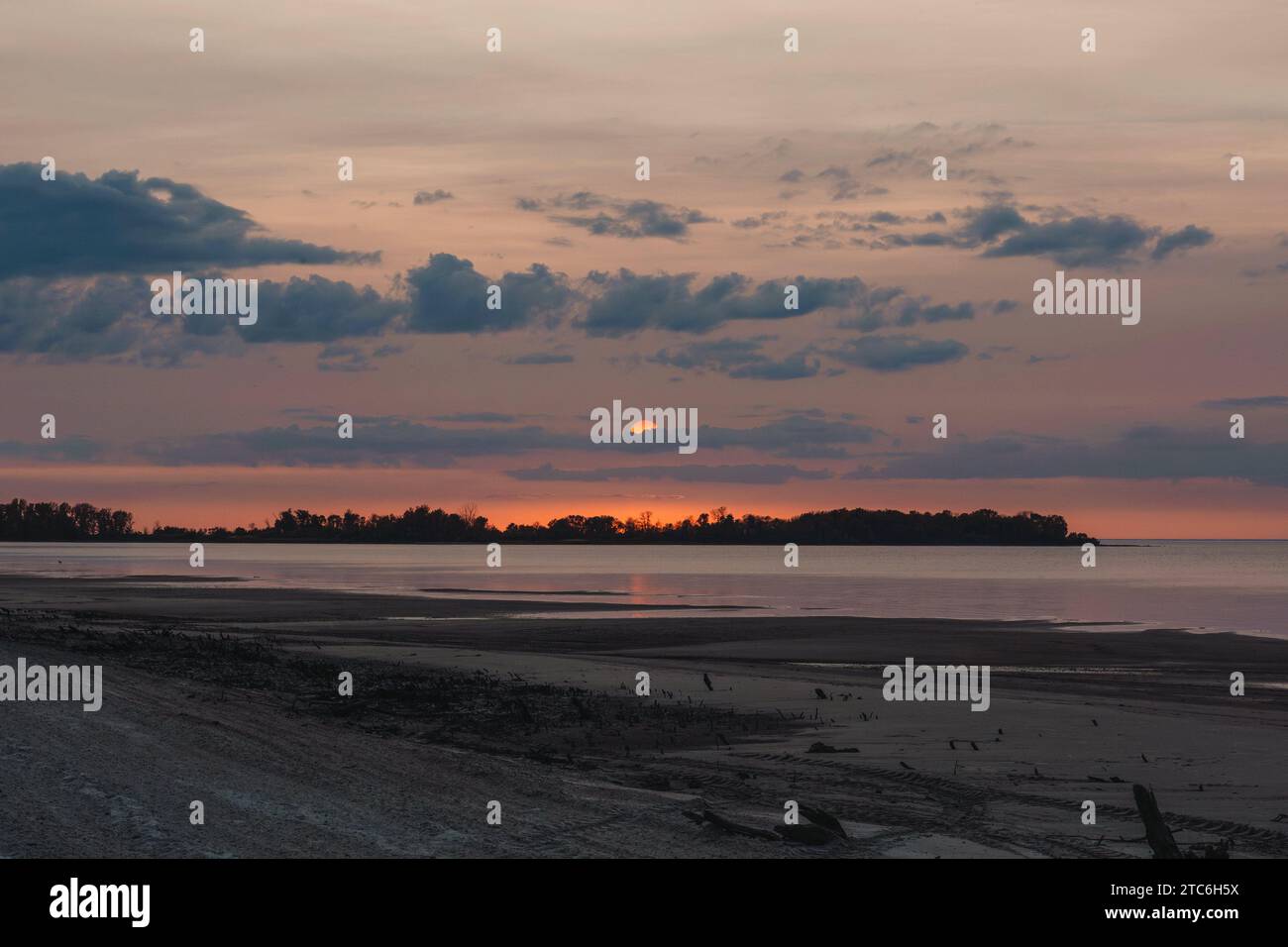 Beach sunset with blue clouds and setting sun Stock Photo - Alamy