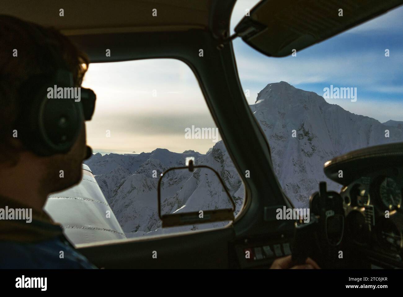 Male pilot looks out window at mountains while flying in Alaska Stock ...