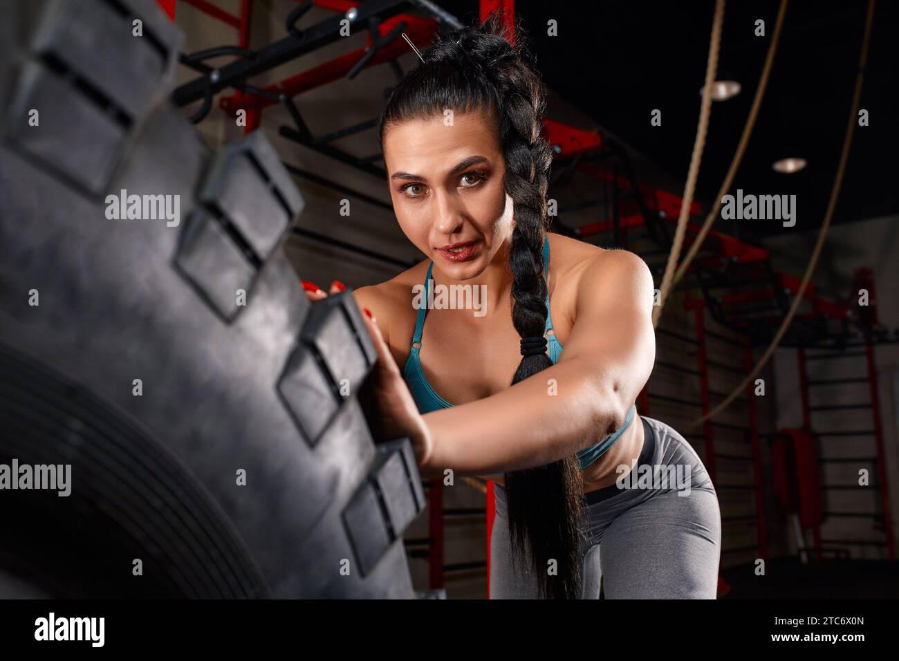 Fit female athlete working out with a huge tire, turning and flipping ...
