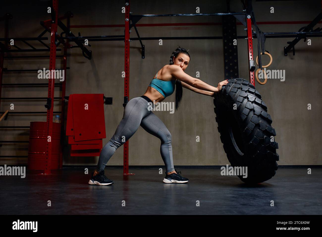 Fit female athlete working out with a huge tire, turning and flipping ...