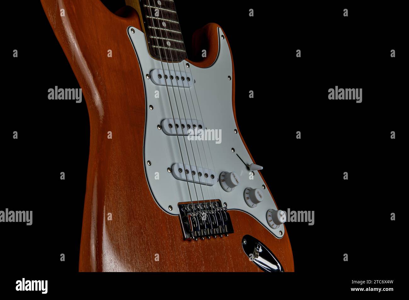 Solid wood electric guitar isolated upright on a black background Stock ...