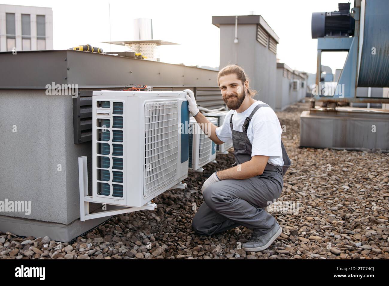 Worker crouching and holding hand on conditioner outdoor Stock Photo ...