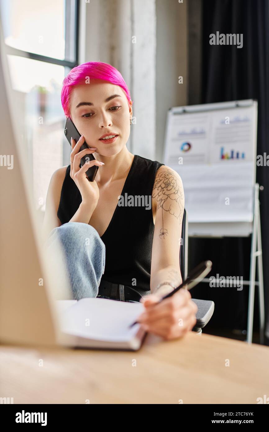 pink haired young female worker in casual outfit taking notes and ...