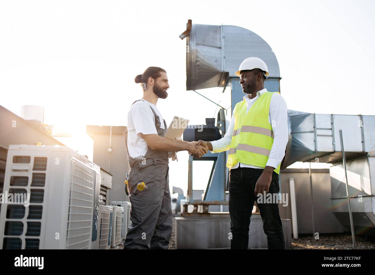 Multicultural workers smiling and shaking hands on roof Stock Photo - Alamy