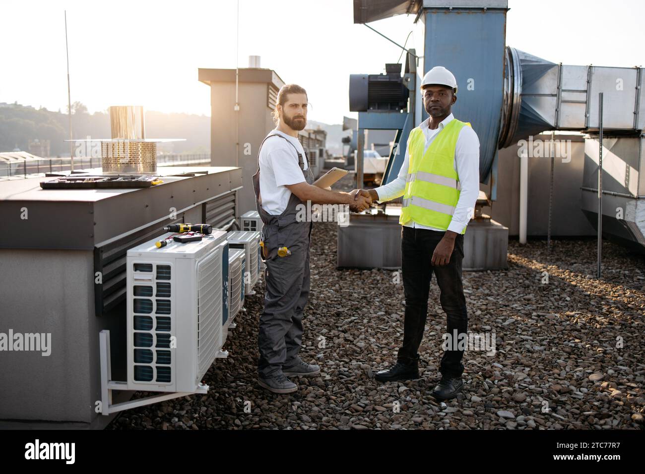 Serious engineers standing and shaking hands while working together on ...