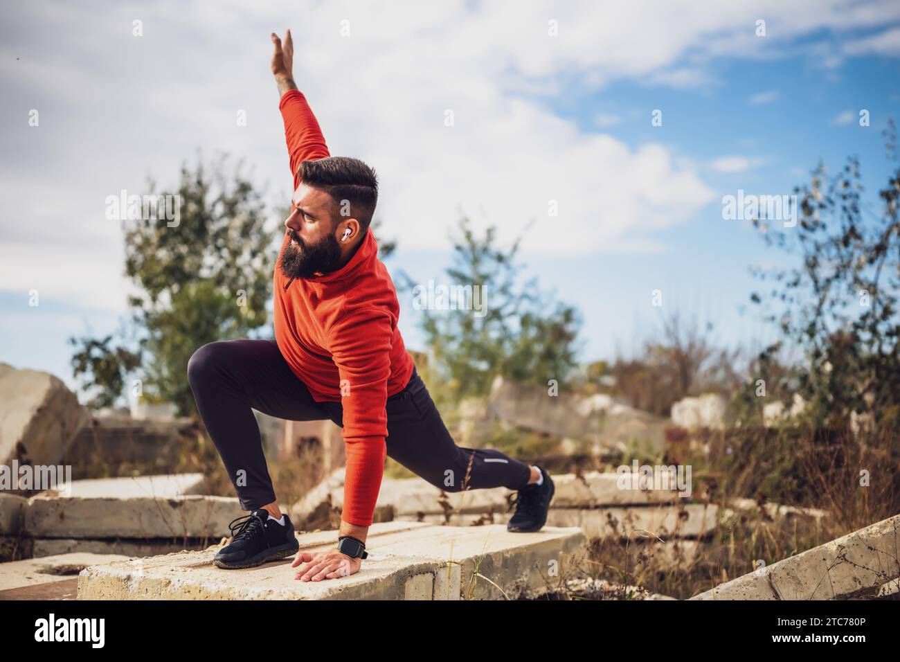 Adult man is exercising outdoor on sunny day. He is stretching his body ...