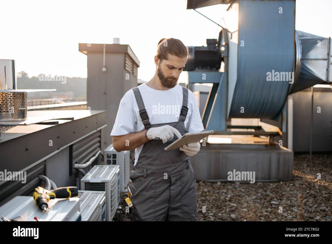 Construction man using tablet while working on rooftop Stock Photo - Alamy