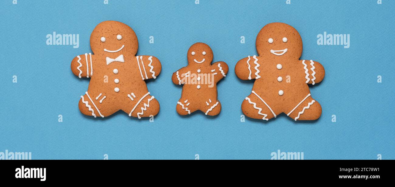 Three gingerbread men cookies on a blue paper background, banner. Top ...