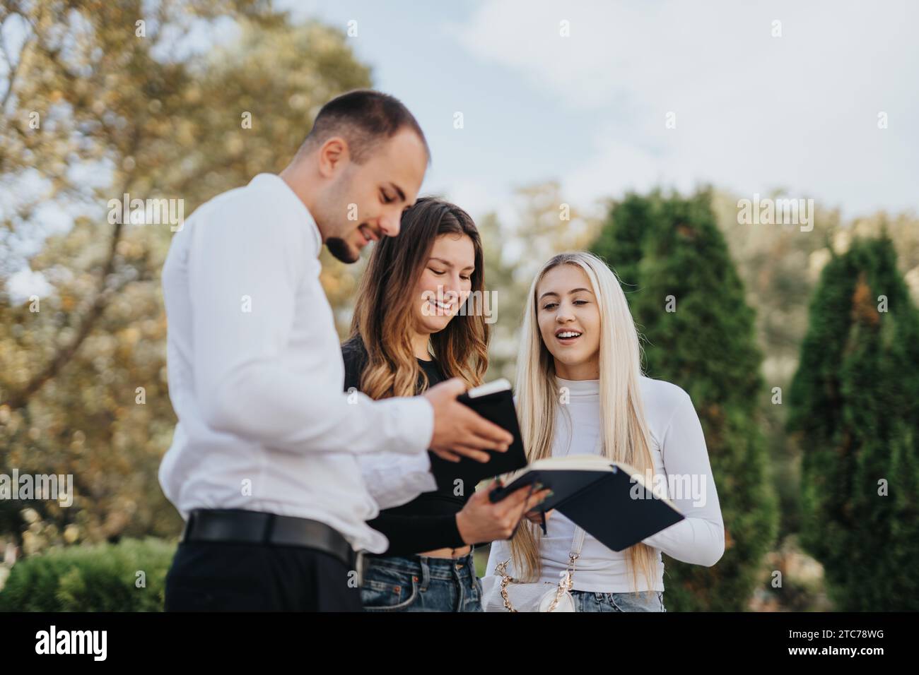University students studying outdoors in a park, discussing subjects ...