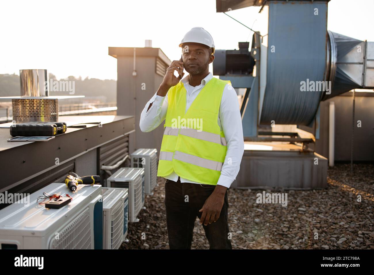 Man engineer standing and talking on smartphone on roof Stock Photo - Alamy