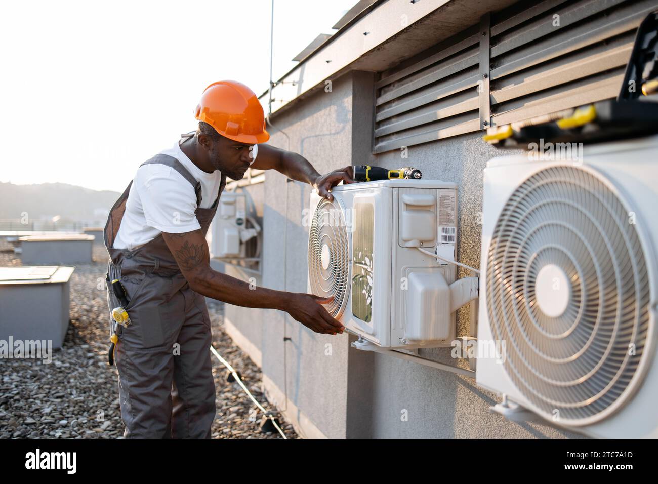 African american factory worker in orange hard hat standing and holding ...