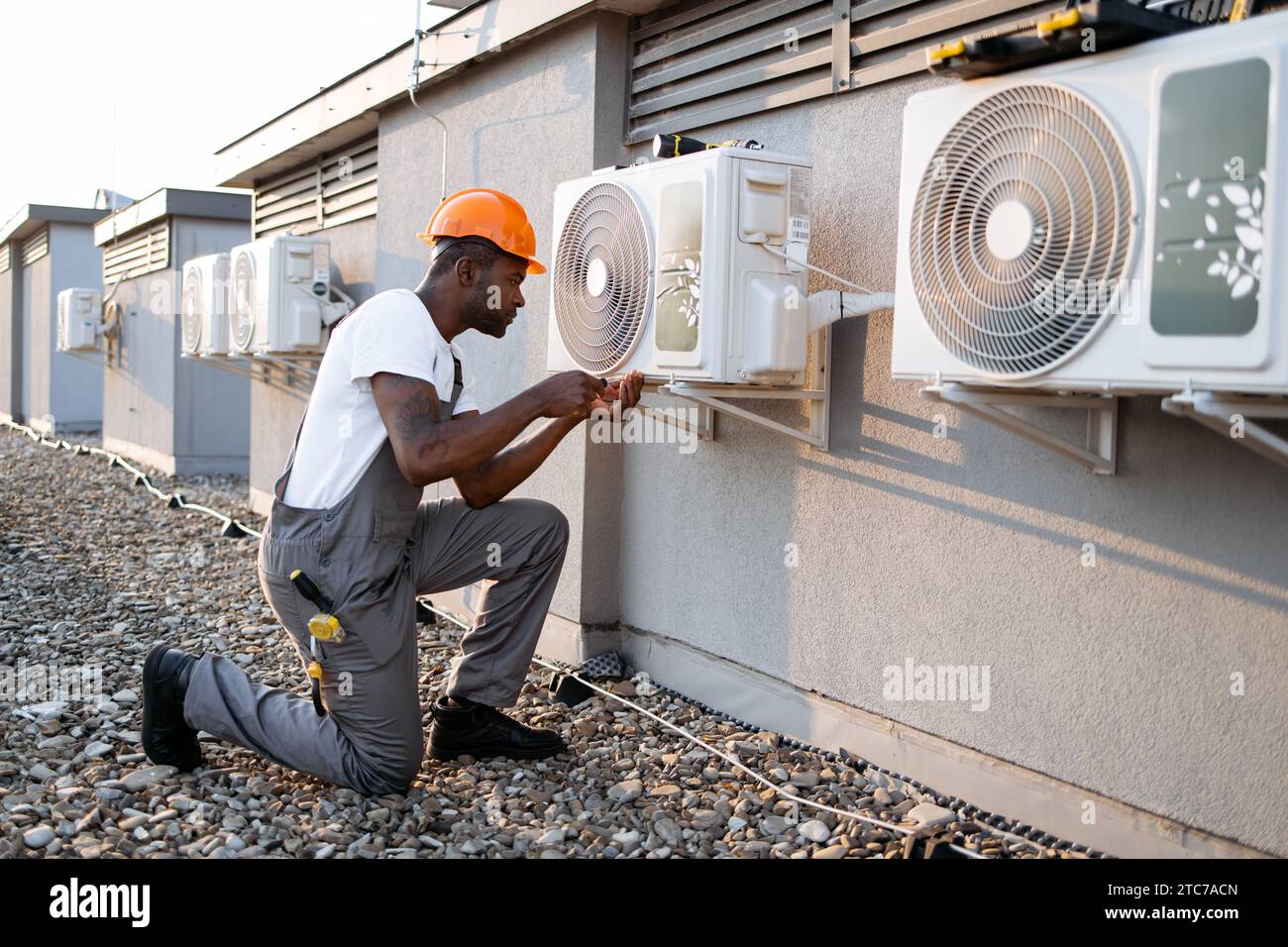 Male builder repairing conditioner with screwdriver on roof Stock Photo ...