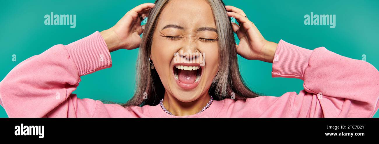 portrait of emotional young asian girl in pink sweatshirt screaming on ...