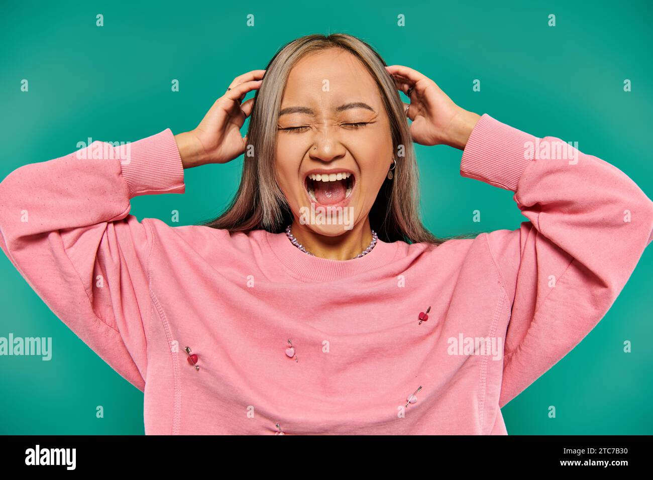 portrait of emotional young asian girl in pink sweatshirt screaming on ...
