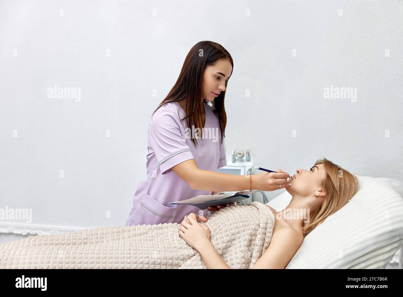 cosmetologist marking skin of caucasian woman with white pencil. facial ...