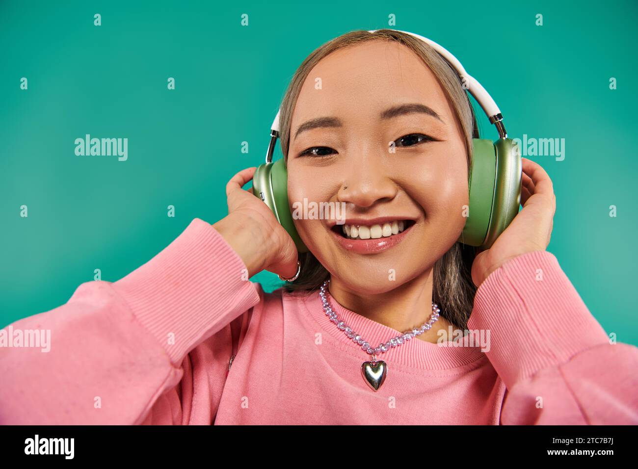 jolly and young asian woman in wireless headphones listening music on ...