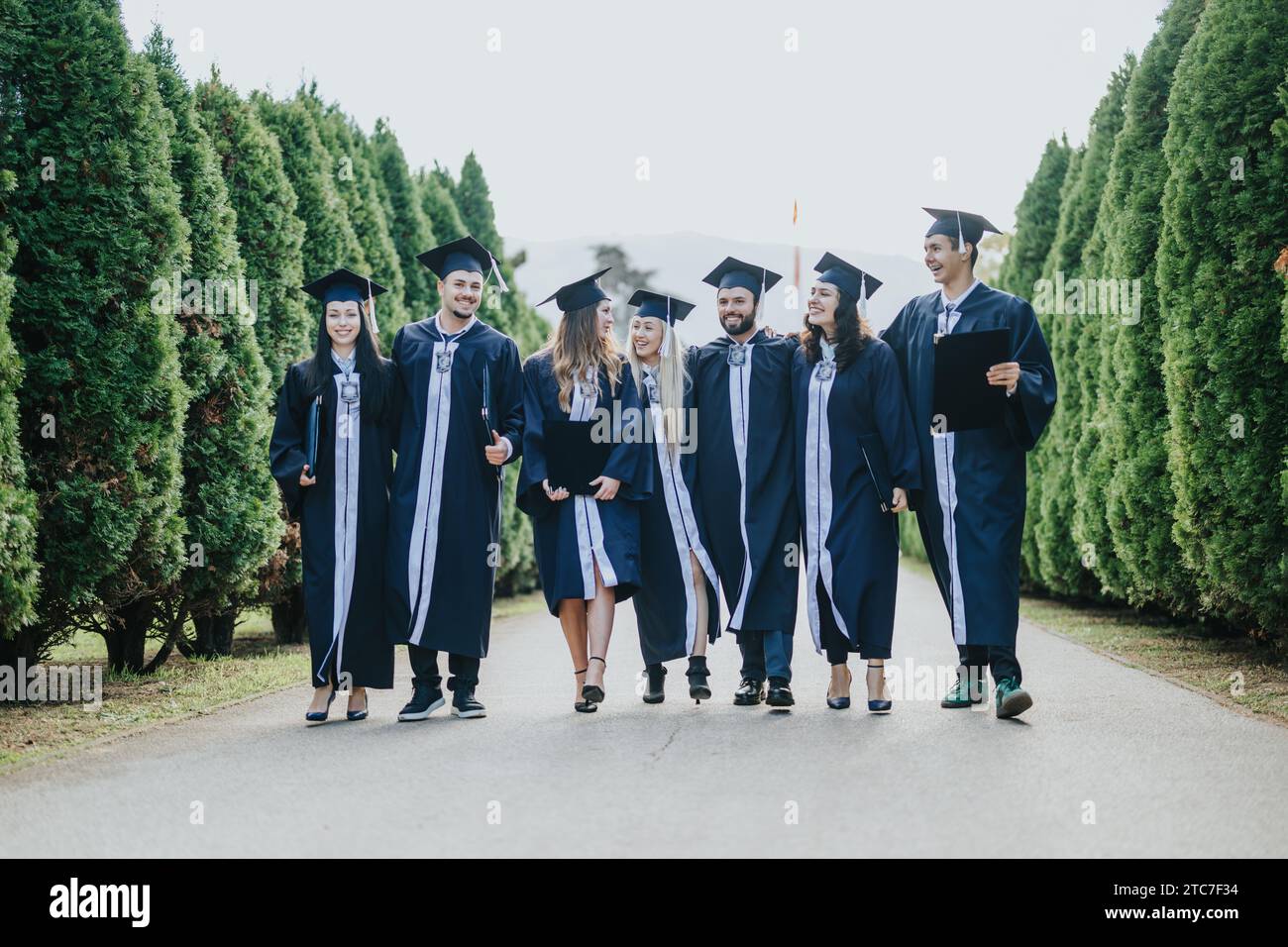 Smiling graduates in gowns and caps celebrate their achievement ...