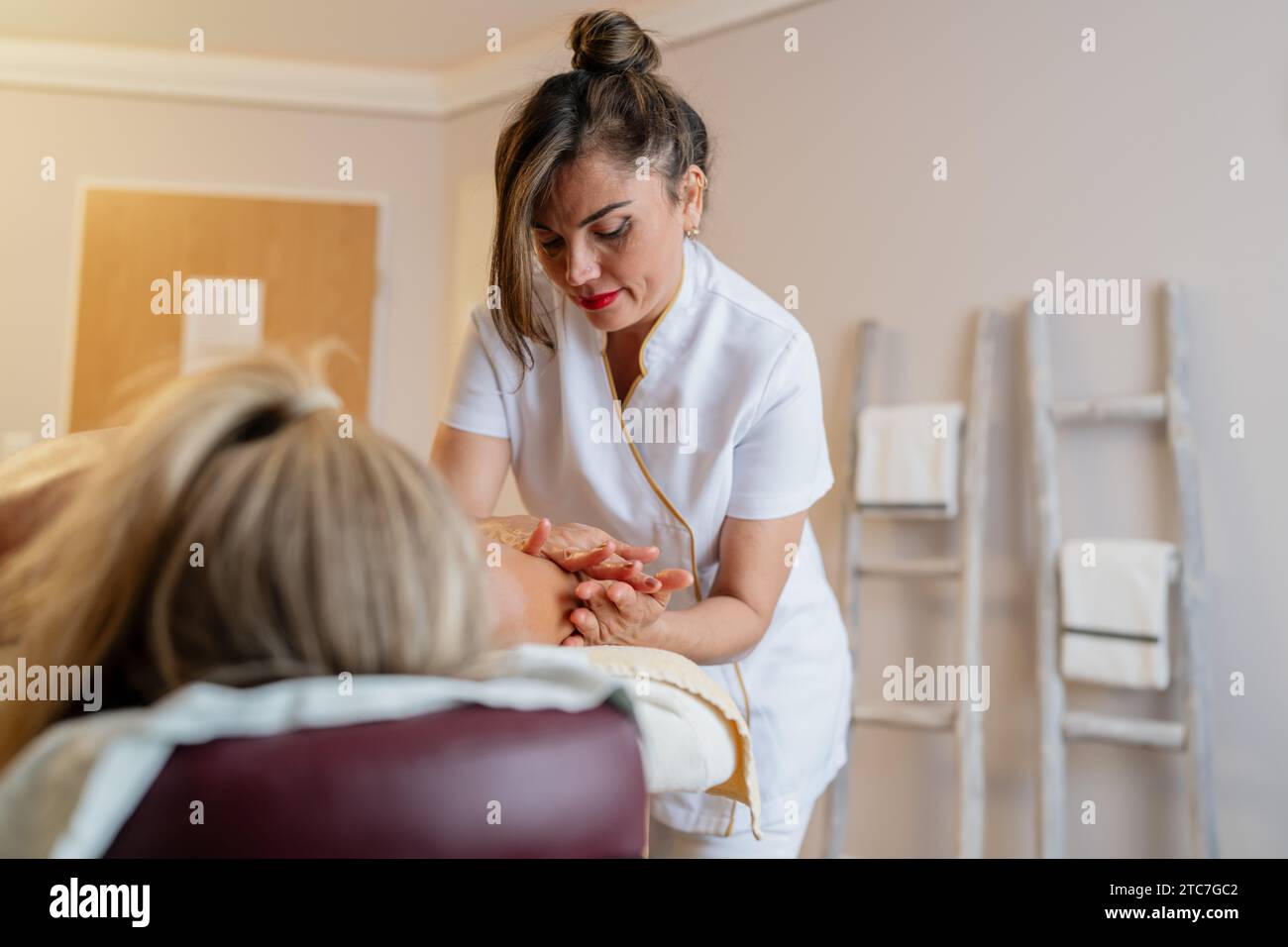Focused massage therapist working on female client's back at a spa ...
