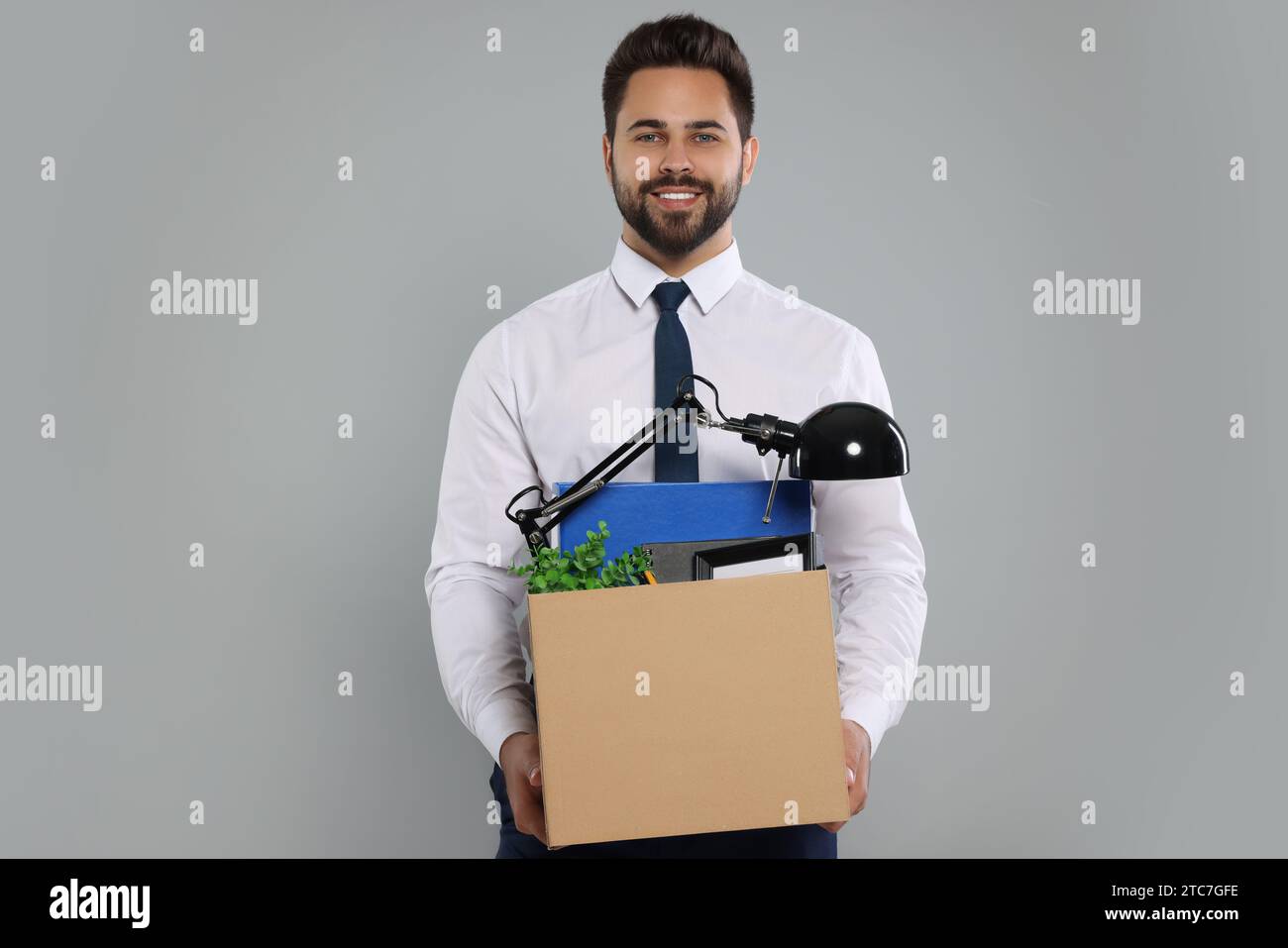 Happy unemployed man with box of personal office belongings on light ...