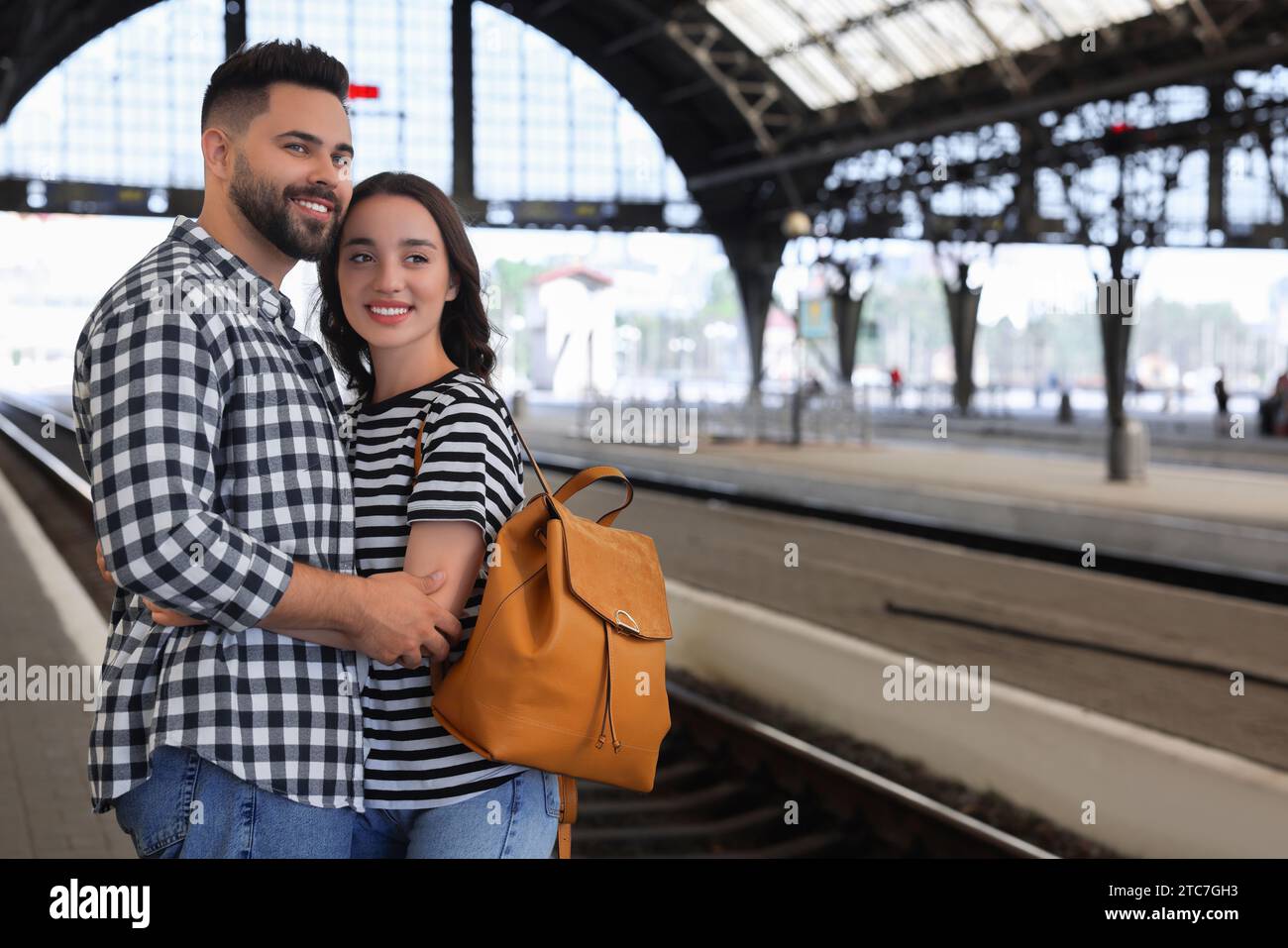 Long-distance relationship. Beautiful couple on platform of railway station, space for text ...