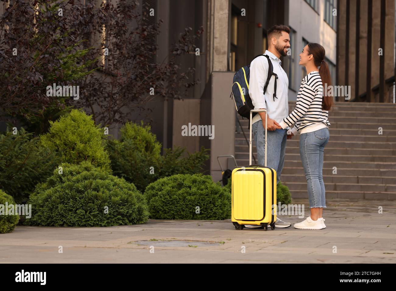 Long-distance relationship. Man with luggage holding hands with his ...