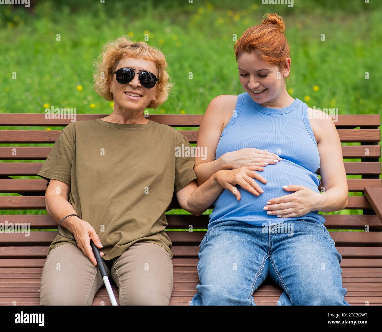 An elderly blind woman holds her pregnant daughter by the belly while ...