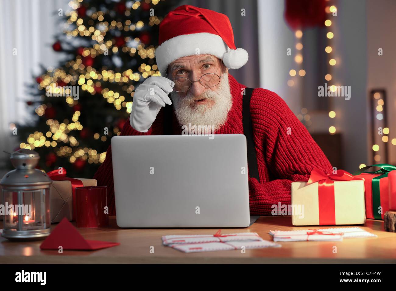 Emotional Santa Claus using laptop at his workplace in room with ...