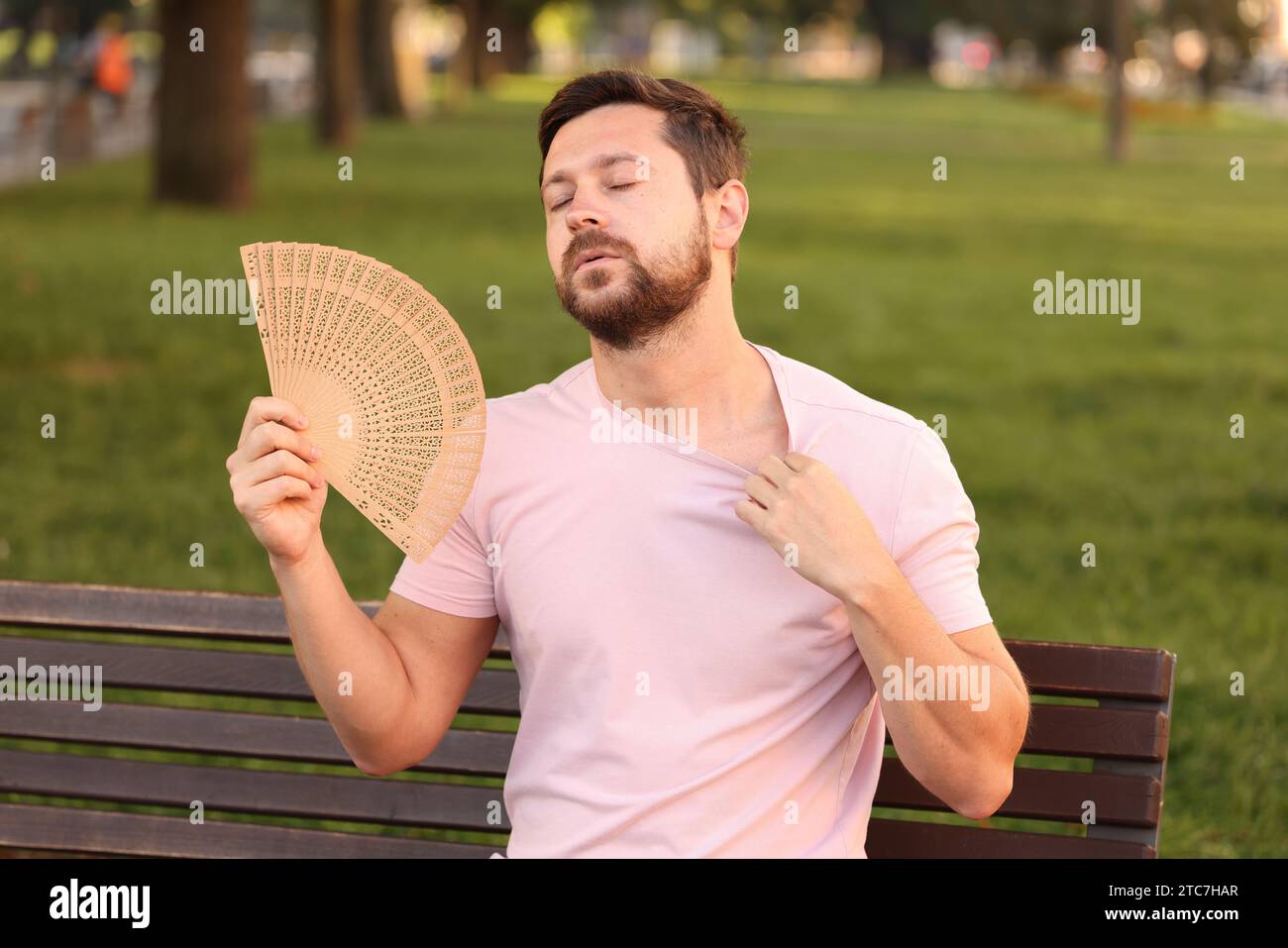 Man with hand fan suffering from heat outdoors Stock Photo - Alamy