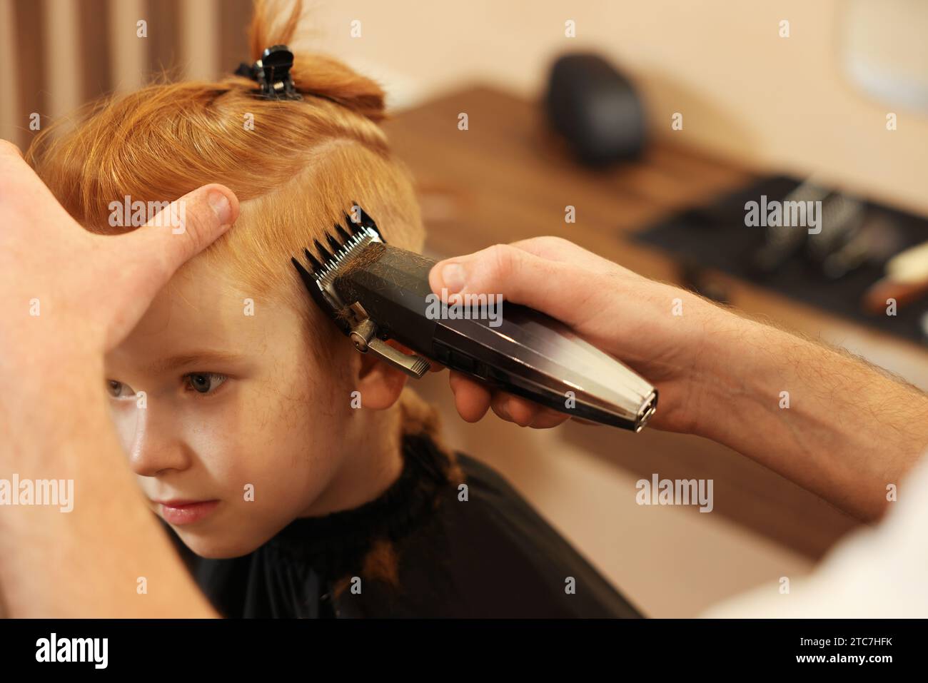 Professional hairdresser cutting boy's hair in beauty salon, closeup ...