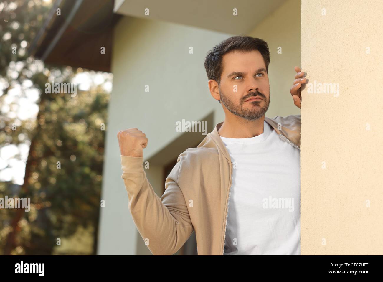 Angry man showing fist near house. Annoying neighbour Stock Photo - Alamy