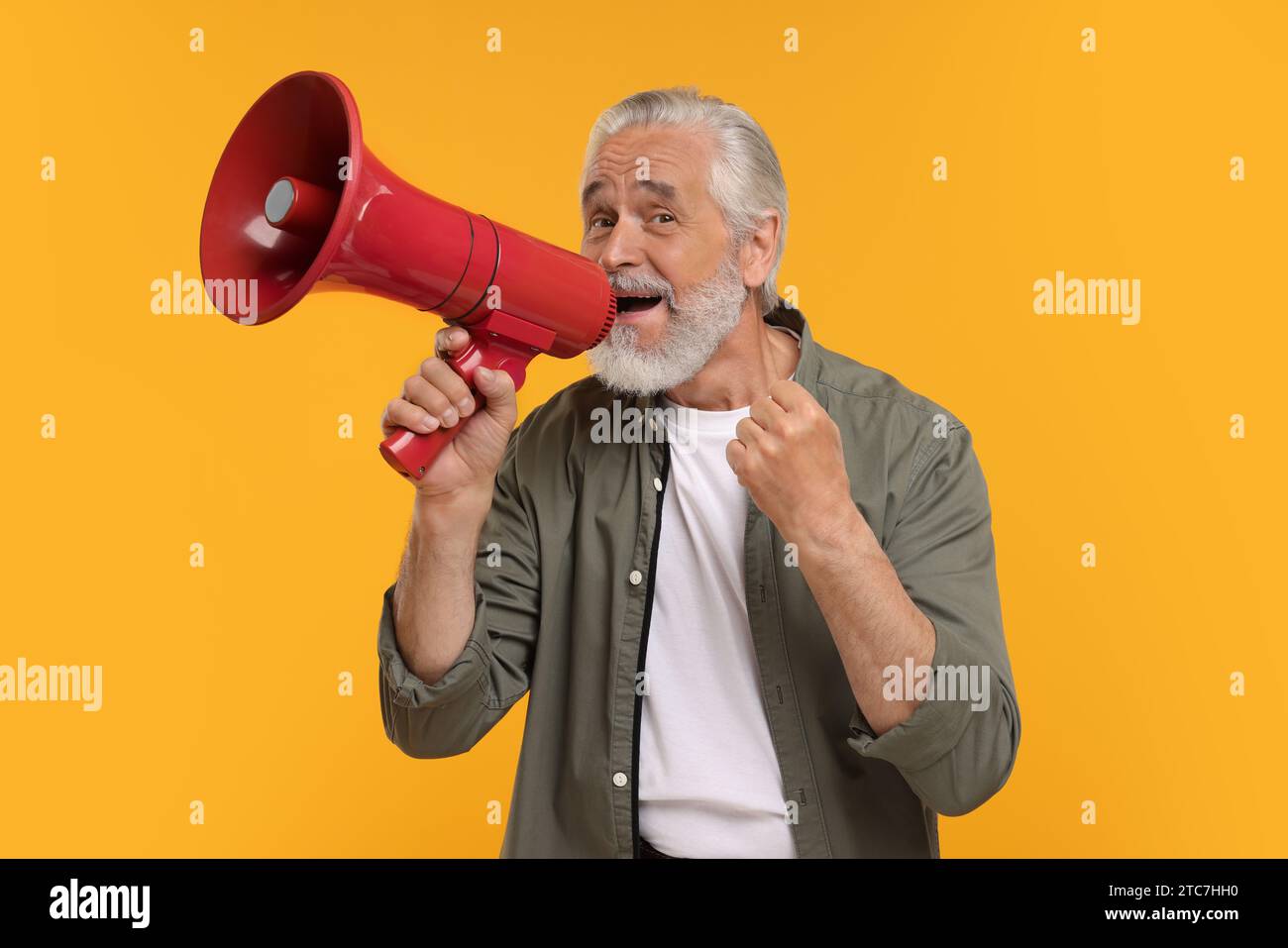 Happy senior sports fan using megaphone on yellow background Stock ...