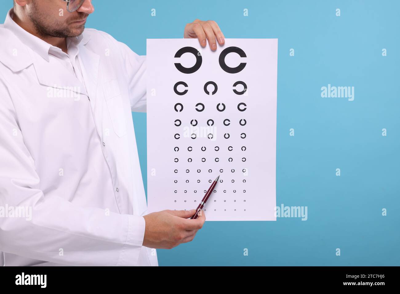 Ophthalmologist pointing at vision test chart on light blue background ...