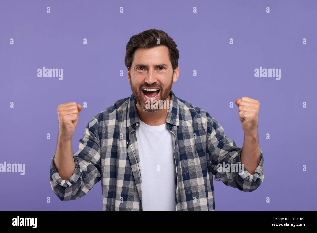 Emotional sports fan celebrating on purple background Stock Photo - Alamy